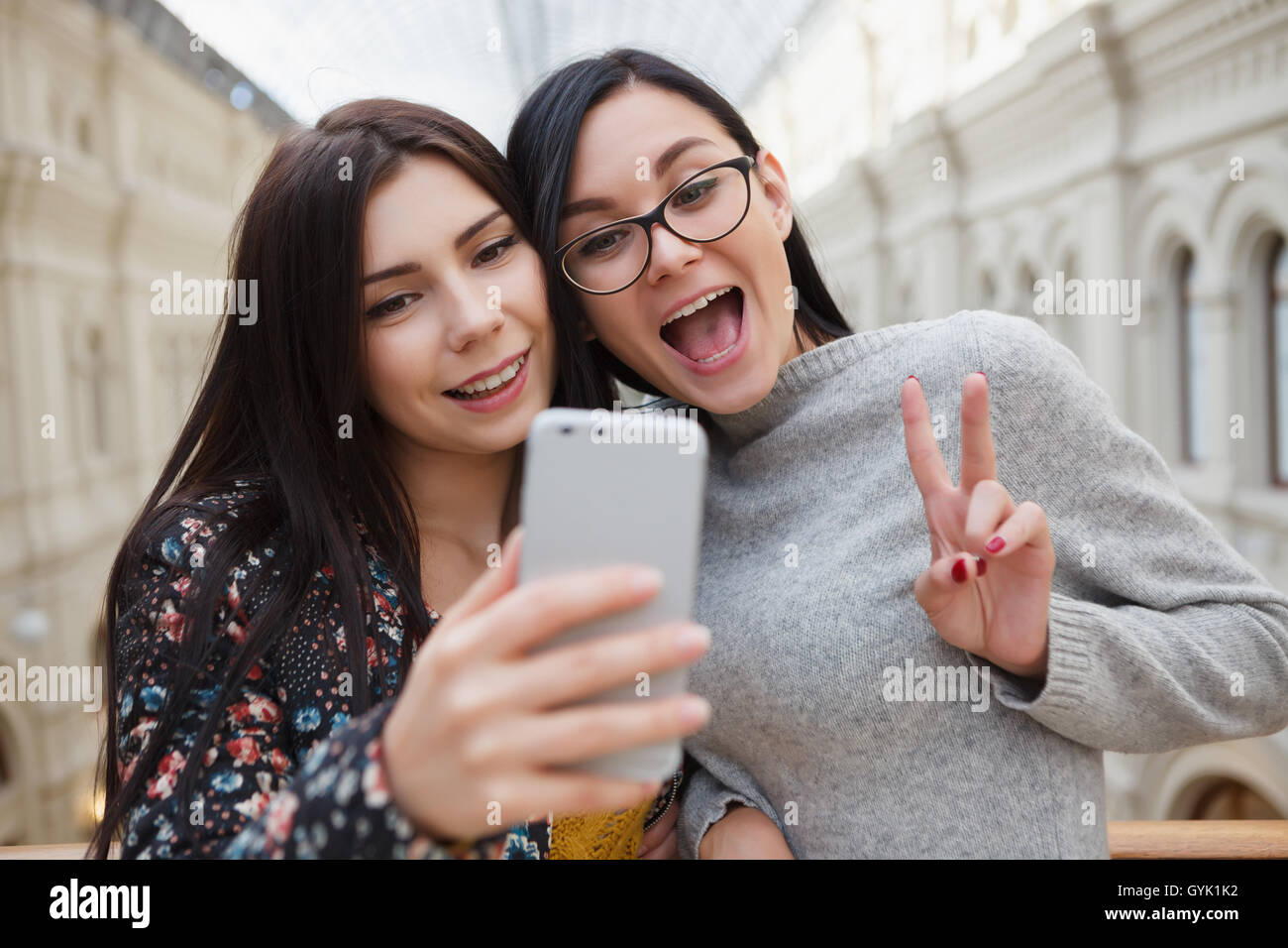 Happy young girl friends taking selfie with modern dual lens camera ...