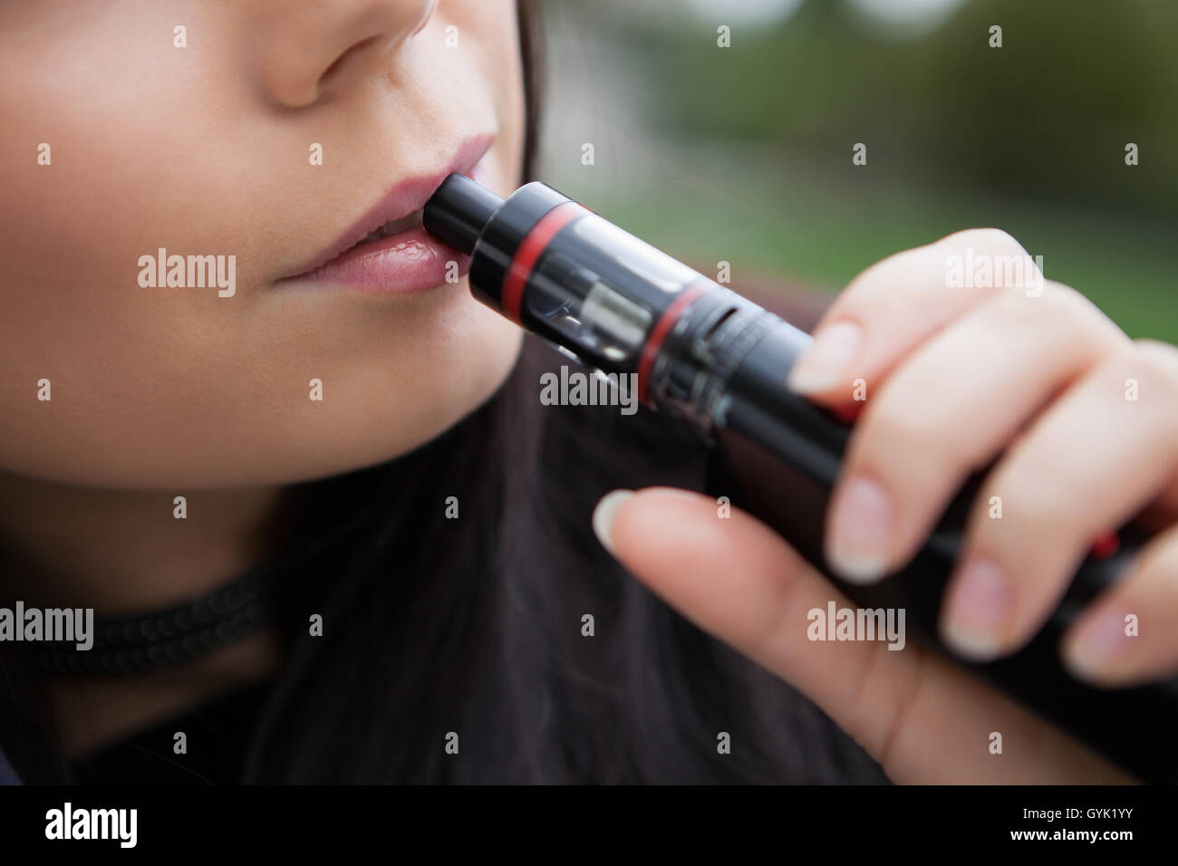 Young pretty girl vaper.Popular vaporizer device e-cig filled with e ...