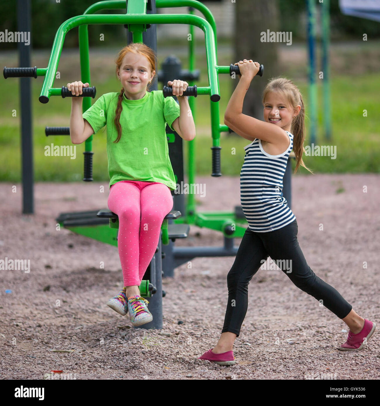 Two little girls is engaged in sport fitness equipment on the ...
