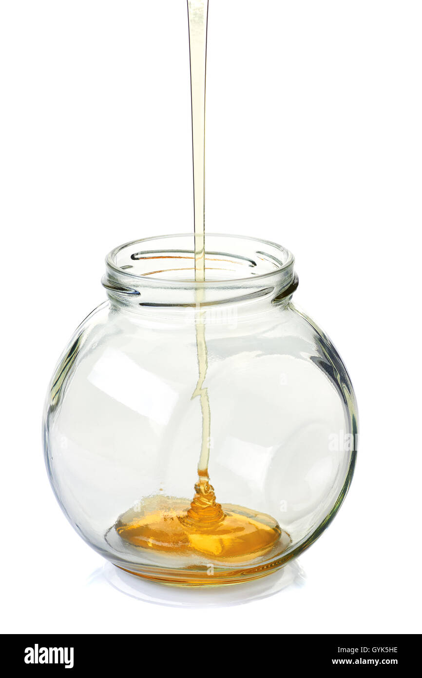 Jar with flowing honey on white Stock Photo - Alamy