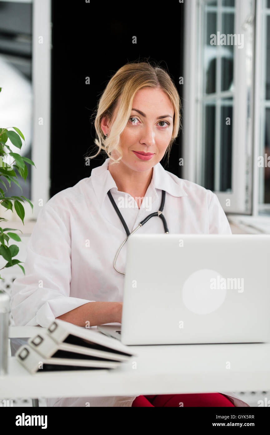 Portrait Of Happy Young Female Doctor Working On Computer at her office ...