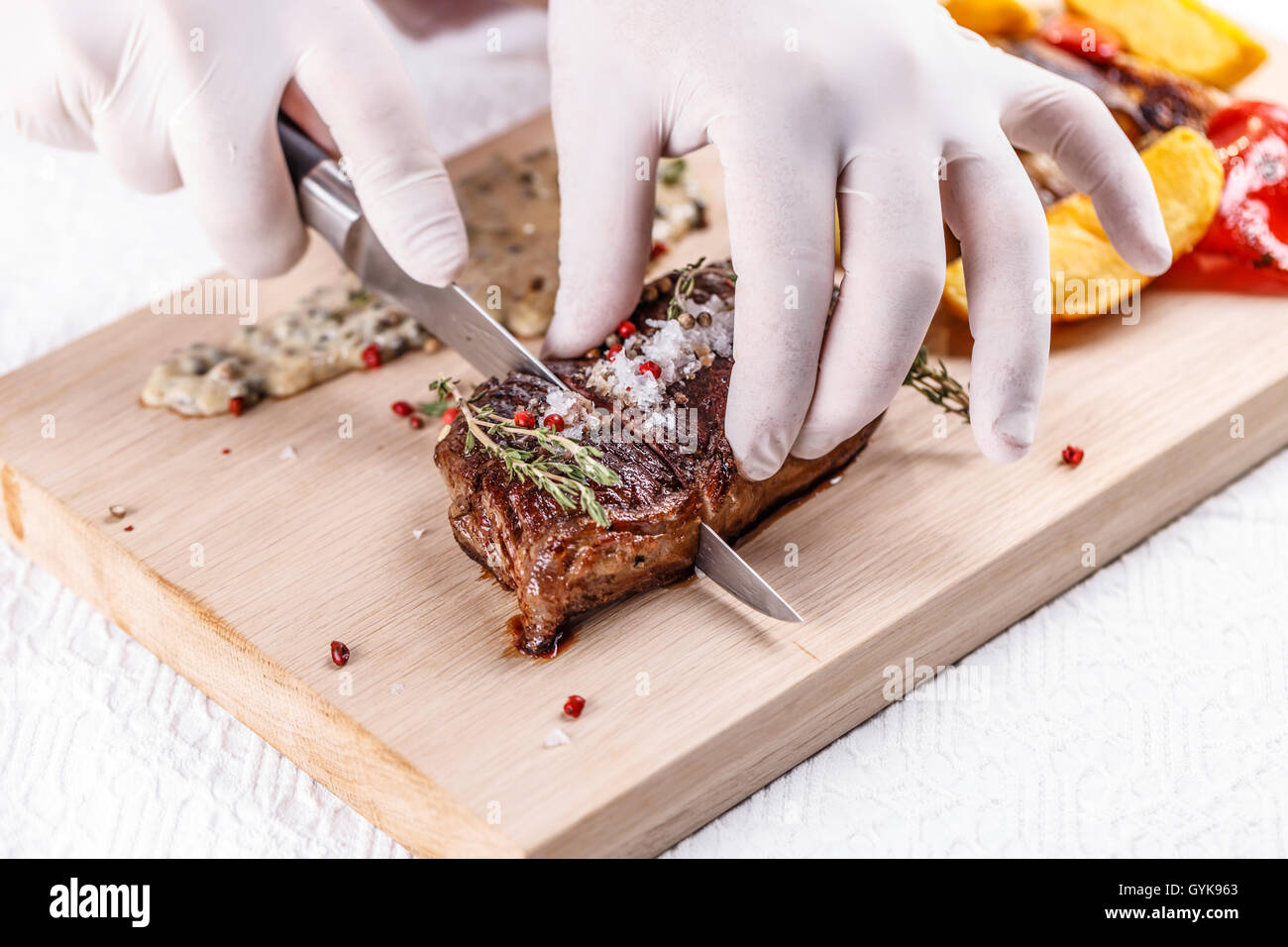 Chef in restaurant kitchen cutting beef steak Stock Photo - Alamy