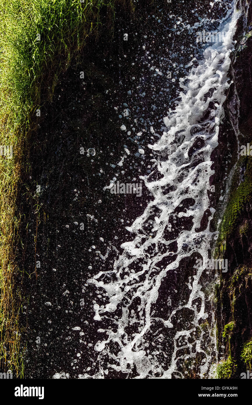 Fresh sparkling water falling over green moss of a beautiful waterfall ...