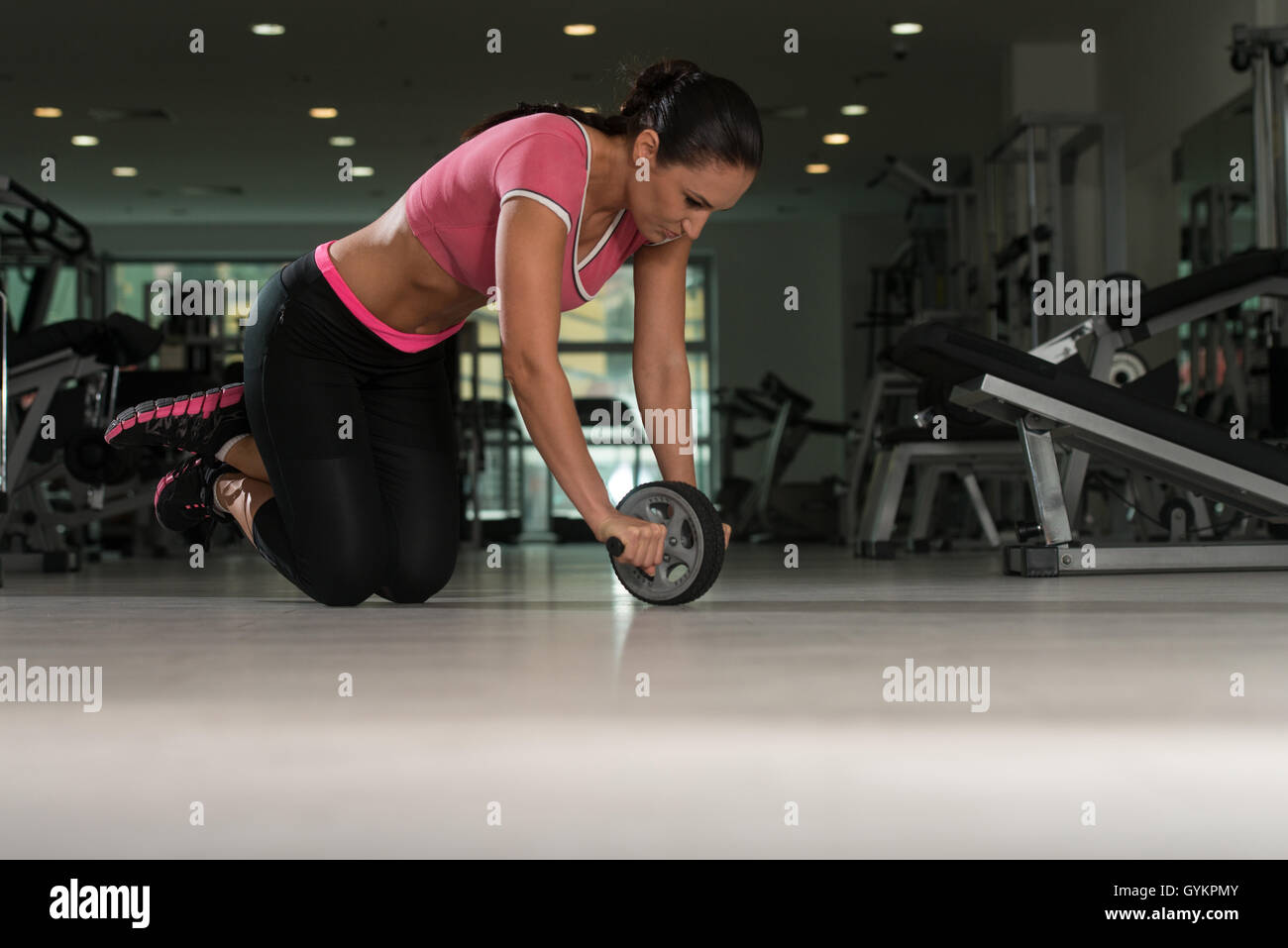 Attractive Woman Exercising With Wheel Roller For Abs On Floor In Gym ...