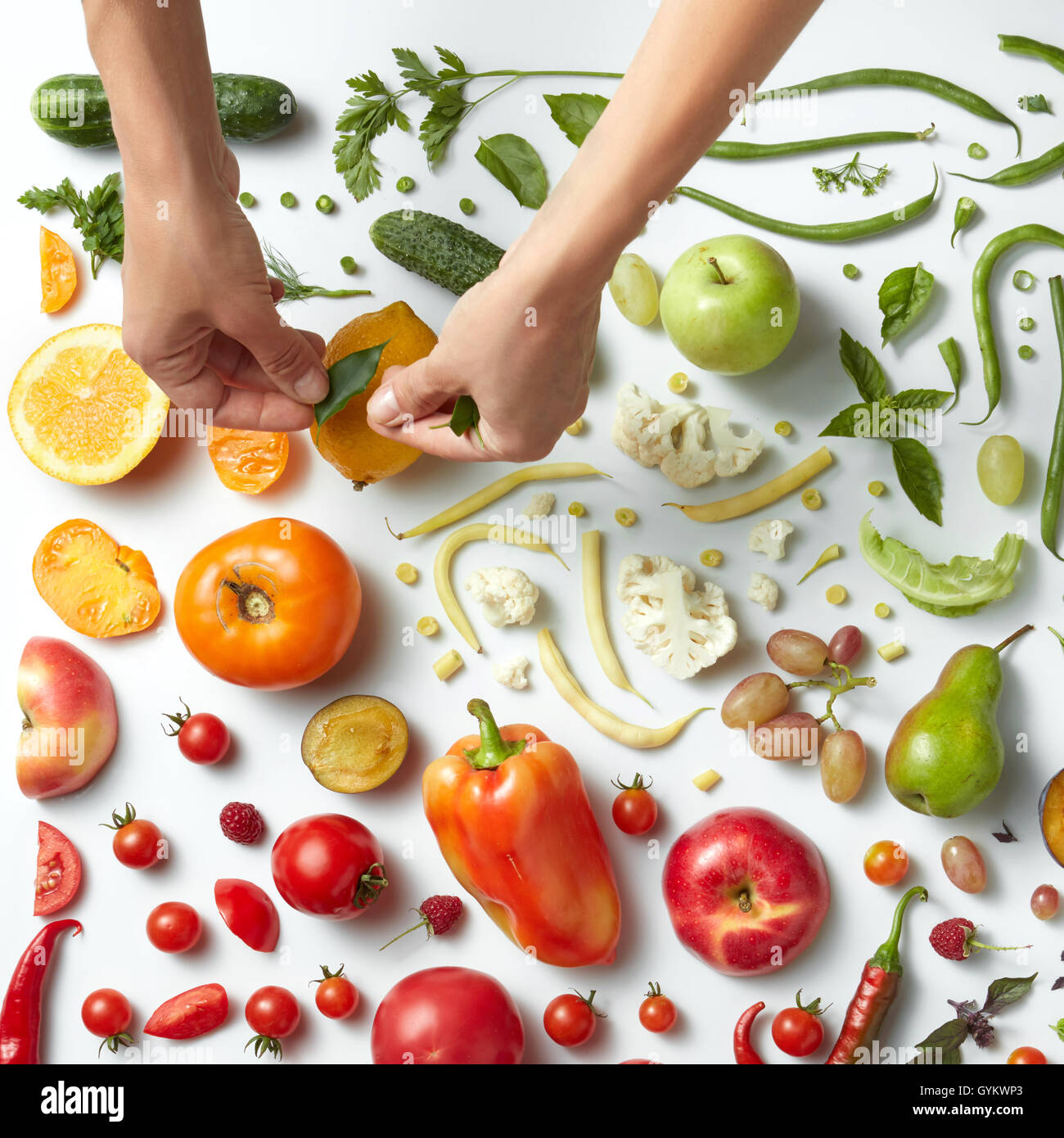 Woman's hand putting different fruits and vegetables on white backdrop ...