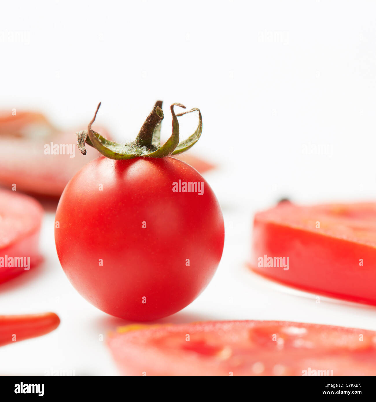Tomato with green tail and sliced tomato rings on a white background ...