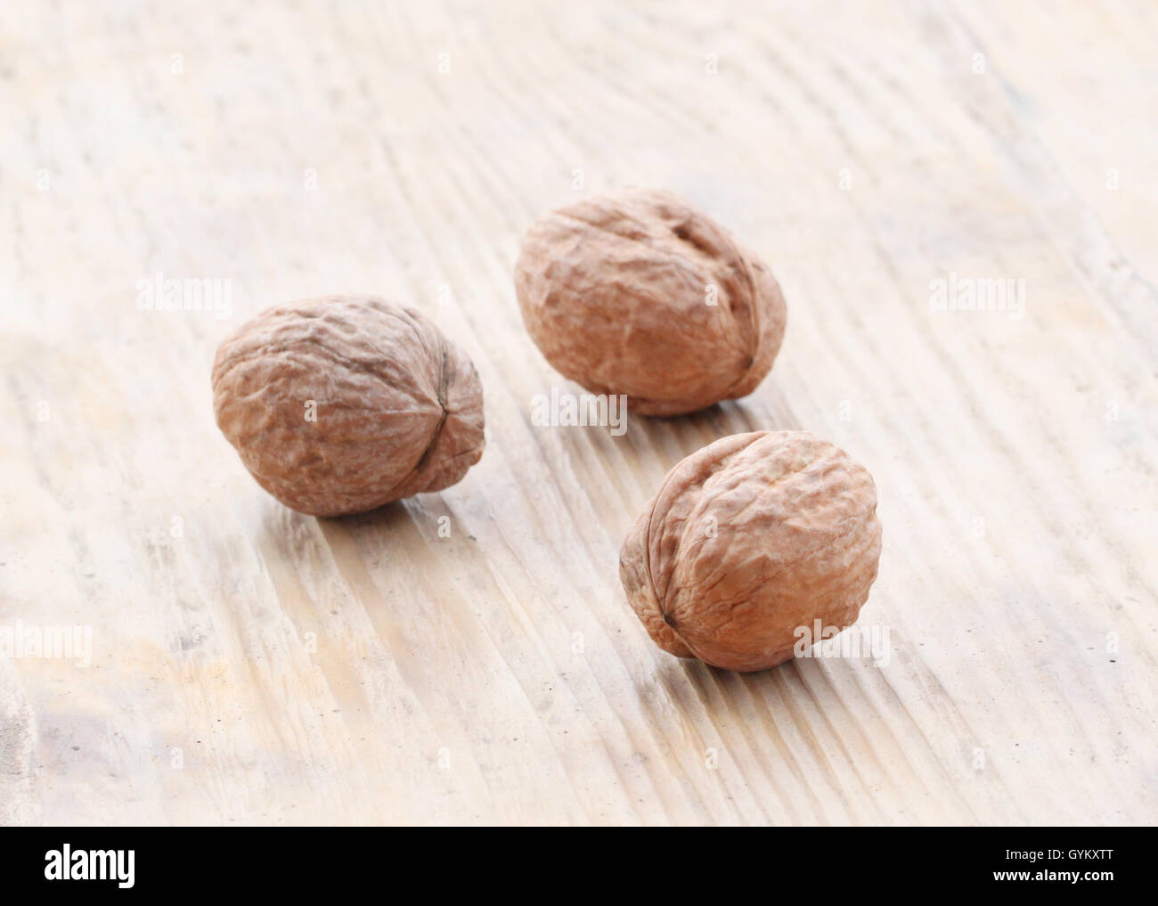 Three walnuts on wooden background Stock Photo - Alamy