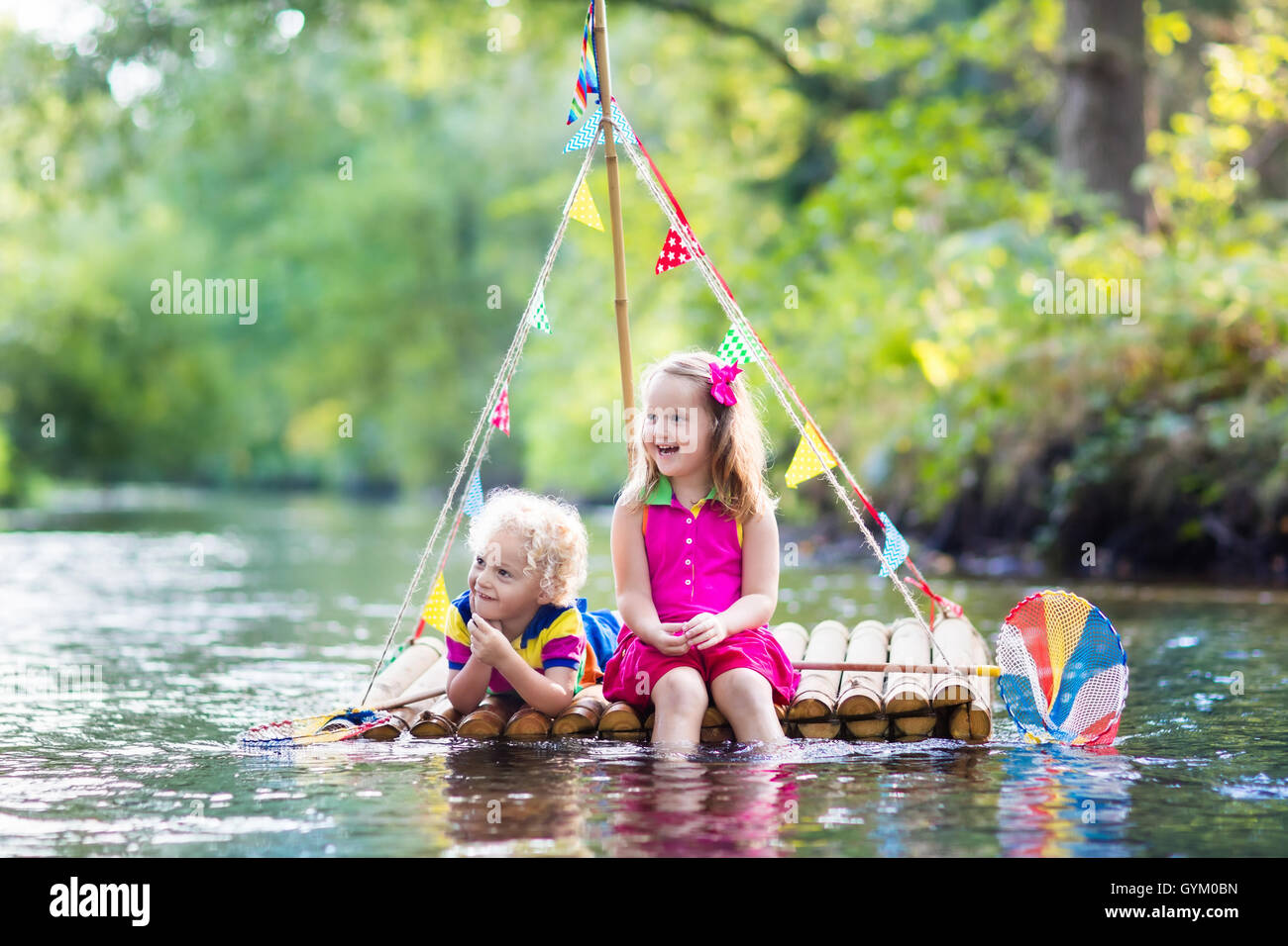 Two children on wooden raft catching fish with a colorful net in a ...