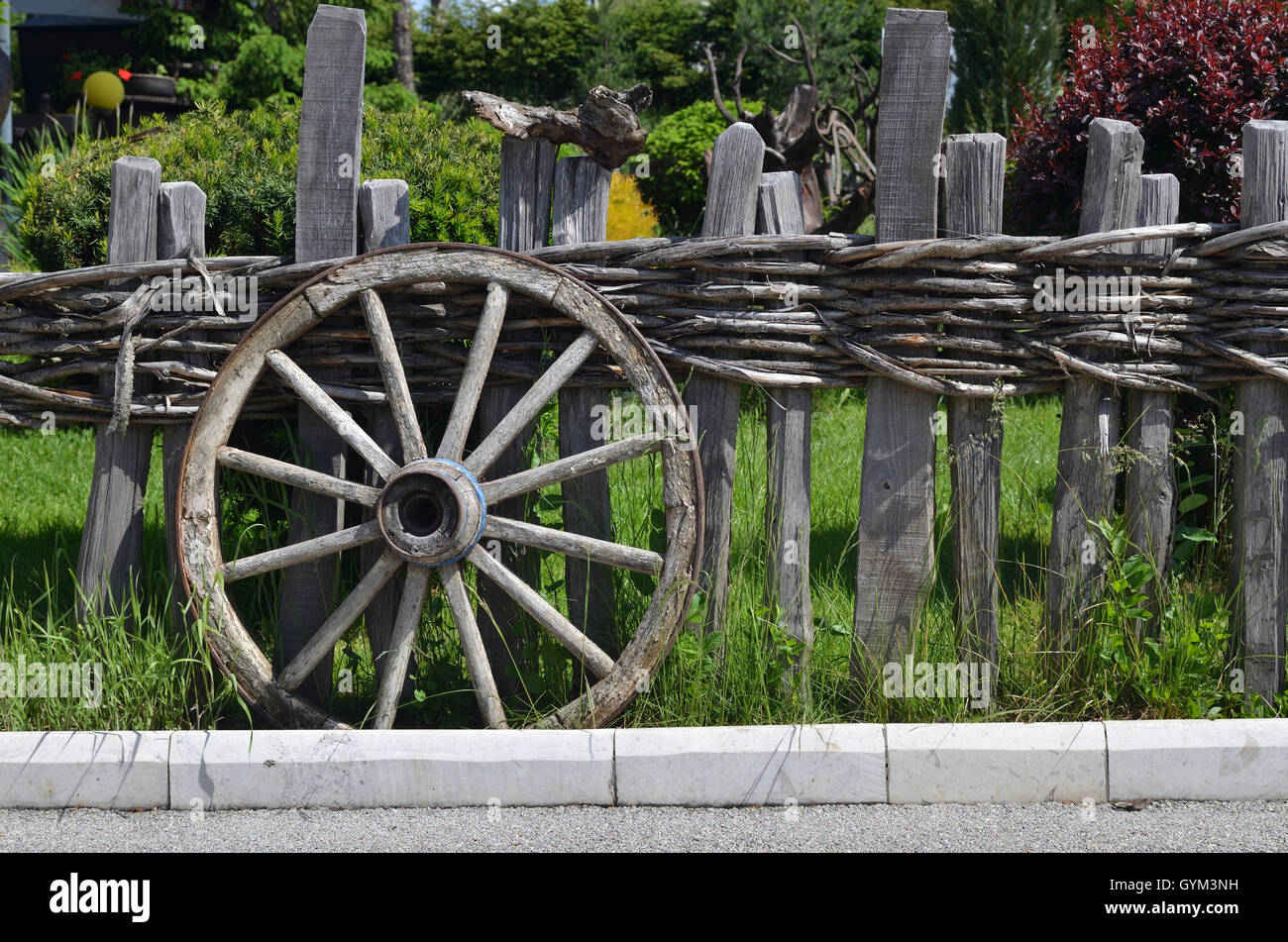 Rustic wheel of a traditional cart leaning on a wooden fence Stock ...