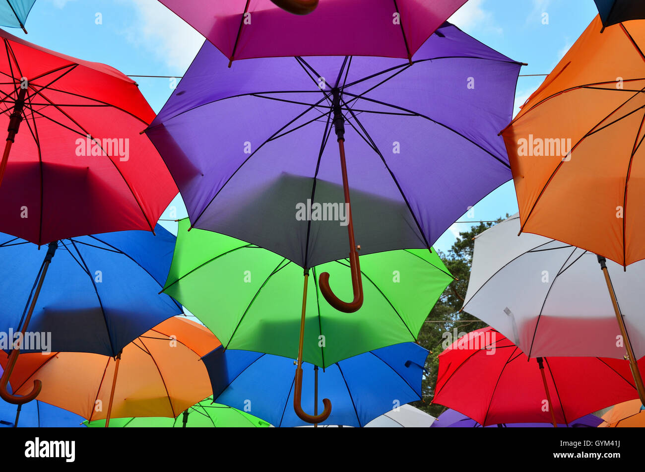 Opened colorful umbrellas with parts of spring blue sky with clouds ...