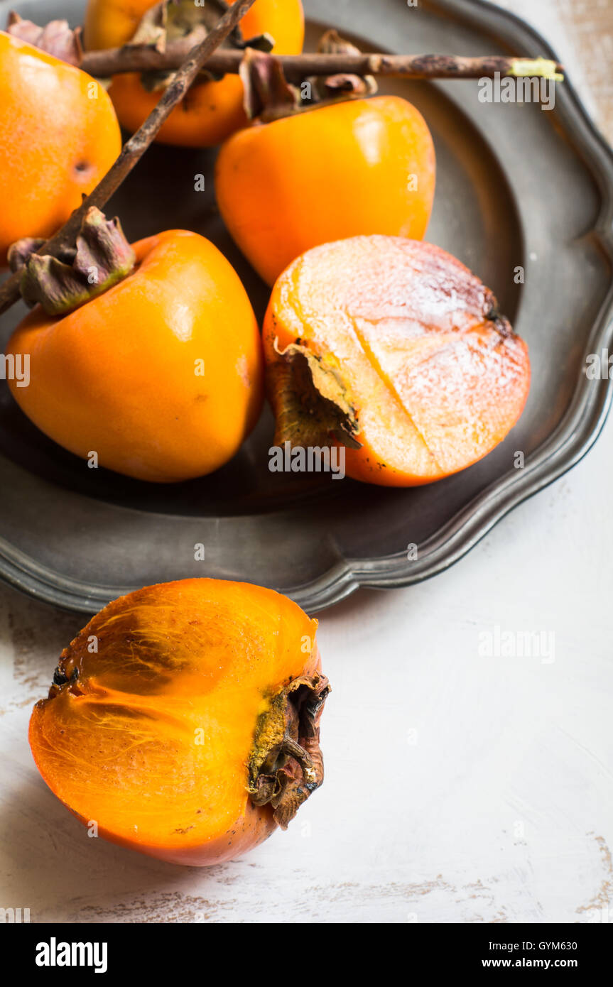 Ripe persimmons fruits on rustic background Stock Photo - Alamy