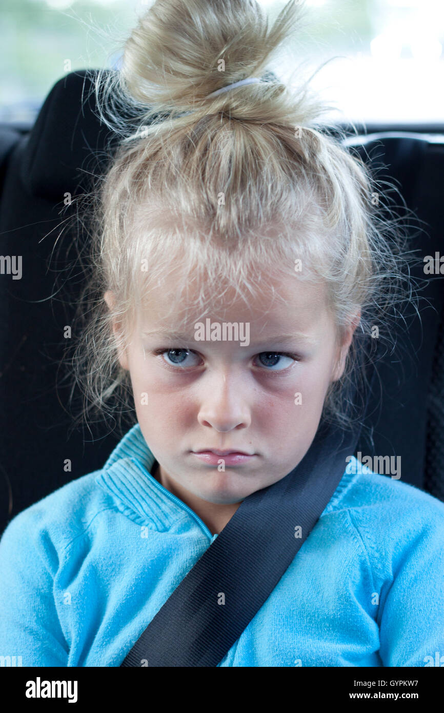 Grumpy kid with seatbelt in car Stock Photo - Alamy