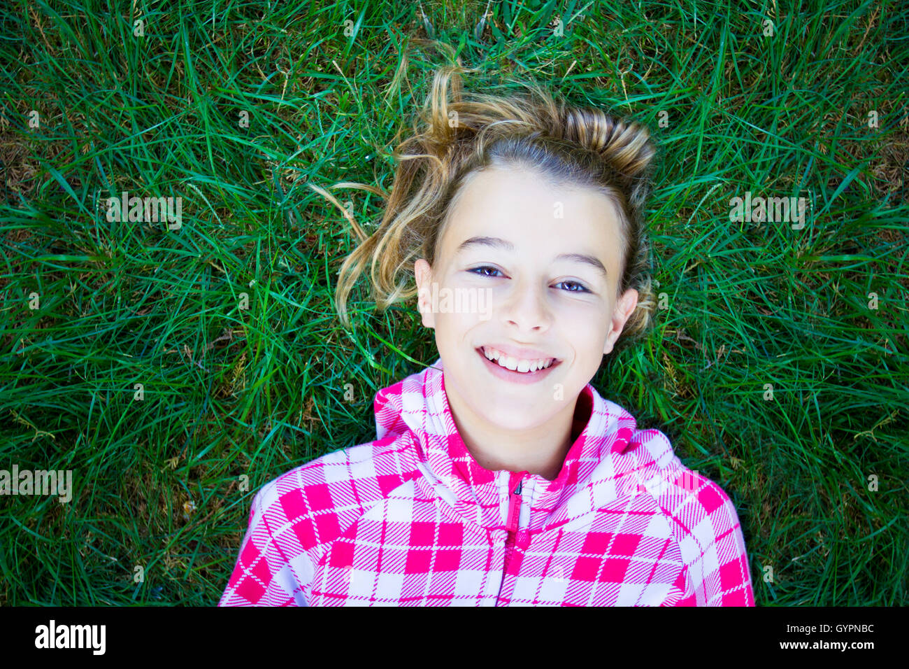Girl lying on grass looking at camera Stock Photo - Alamy