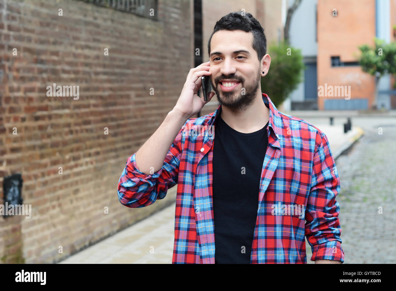 Handsome young latin man talking on the phone. Trendy and urban scene ...