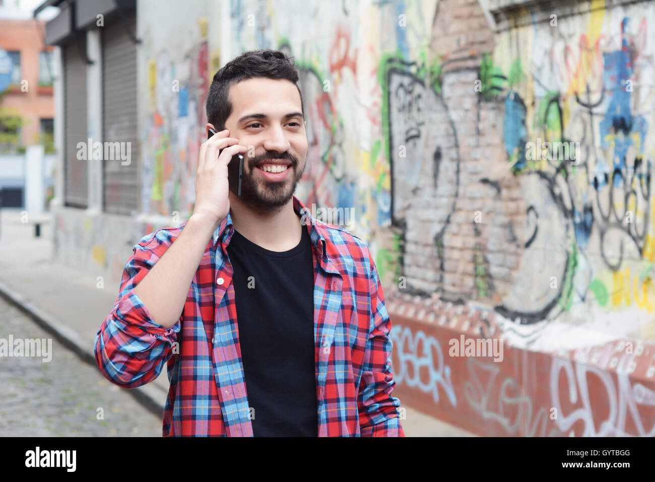 Handsome young latin man talking on the phone. Trendy and urban scene ...