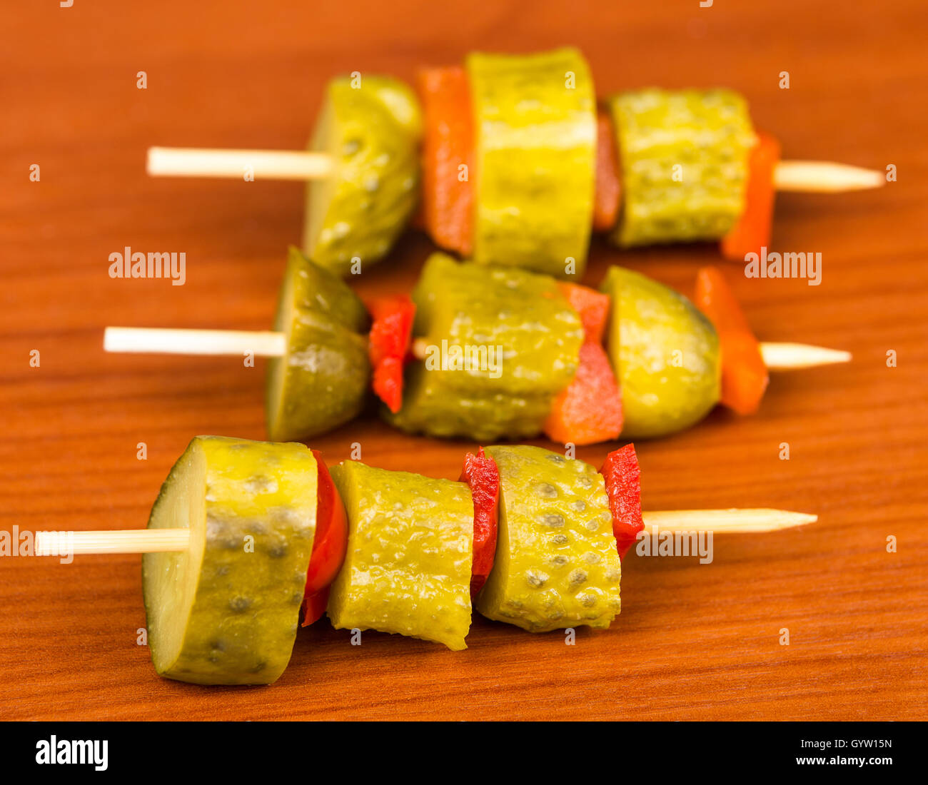 Vegetable skewers of pickles and capiscum lying on wooden surface as ...