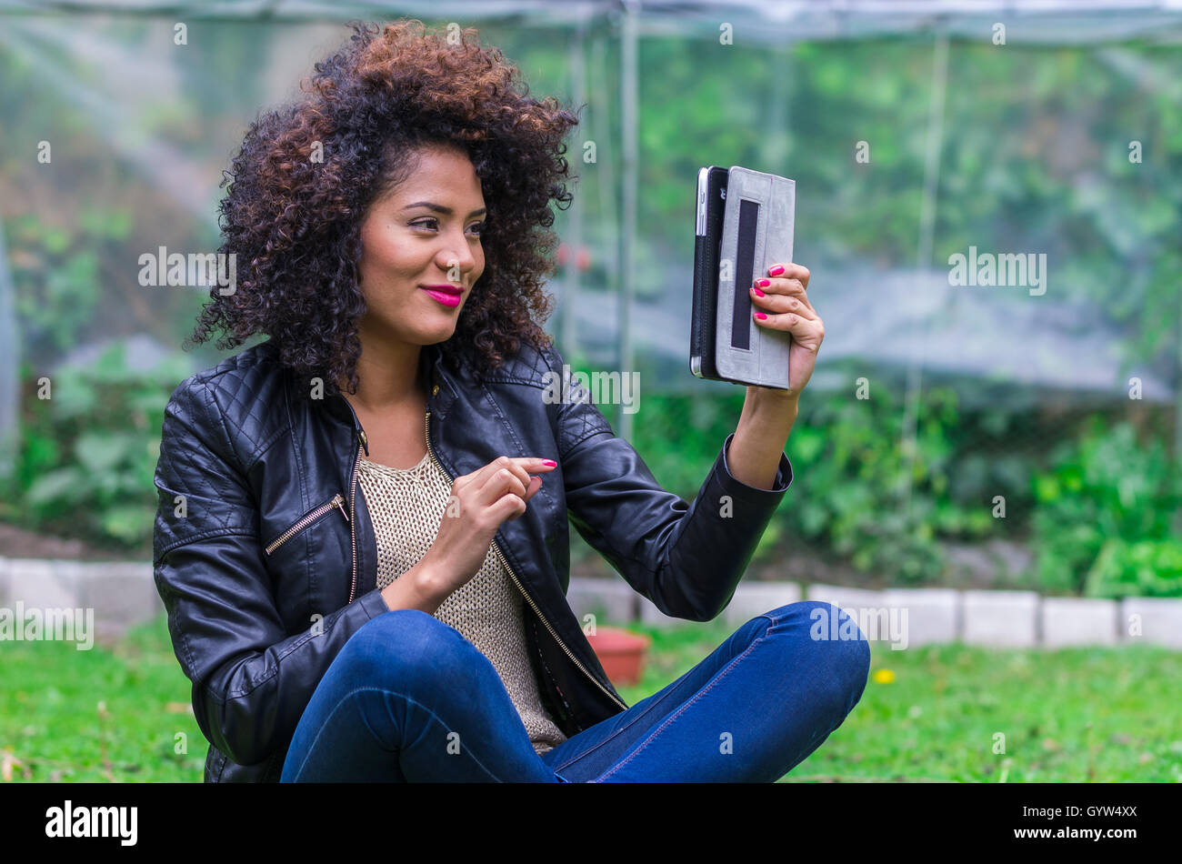 exotic beautiful young girl sitting in the garden using tablet Stock ...