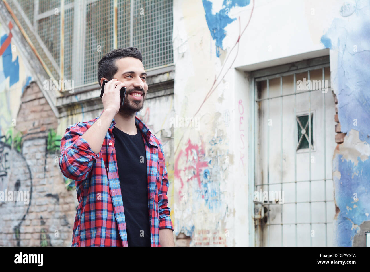 Handsome young latin man talking on the phone. Trendy and urban scene ...