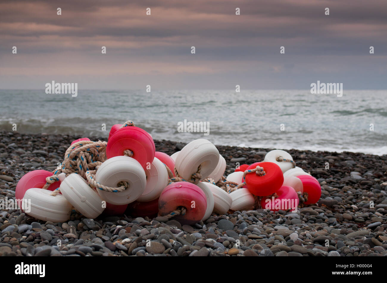 Red and white pile of fishing floats on the beach Stock Photo - Alamy