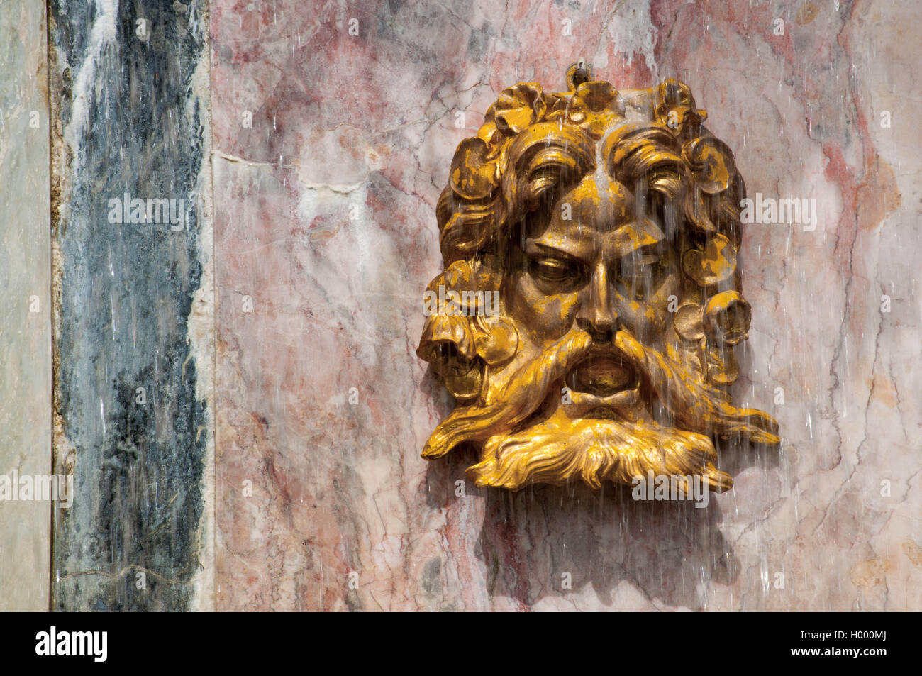Golden fountain face of Neptune on marble wall Stock Photo - Alamy