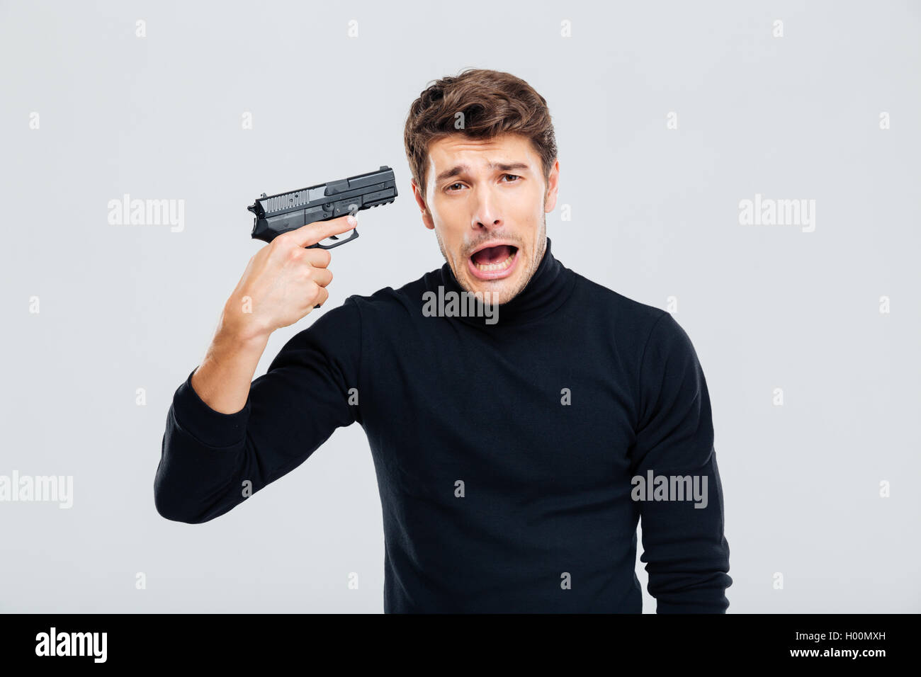 Young handsome man holding hand gun hi-res stock photography and images ...