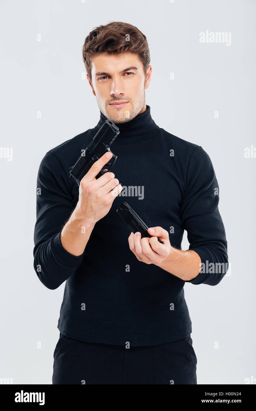 Serious young man standing and loading a gun Stock Photo - Alamy