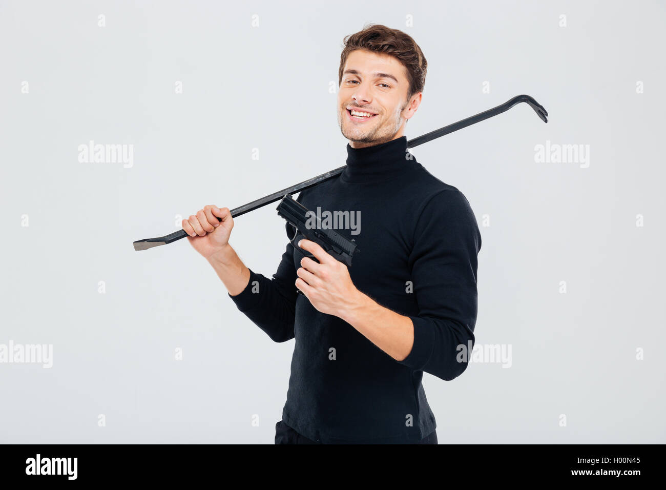 Smiling criminal burglar standing with gun and crowbar Stock Photo - Alamy