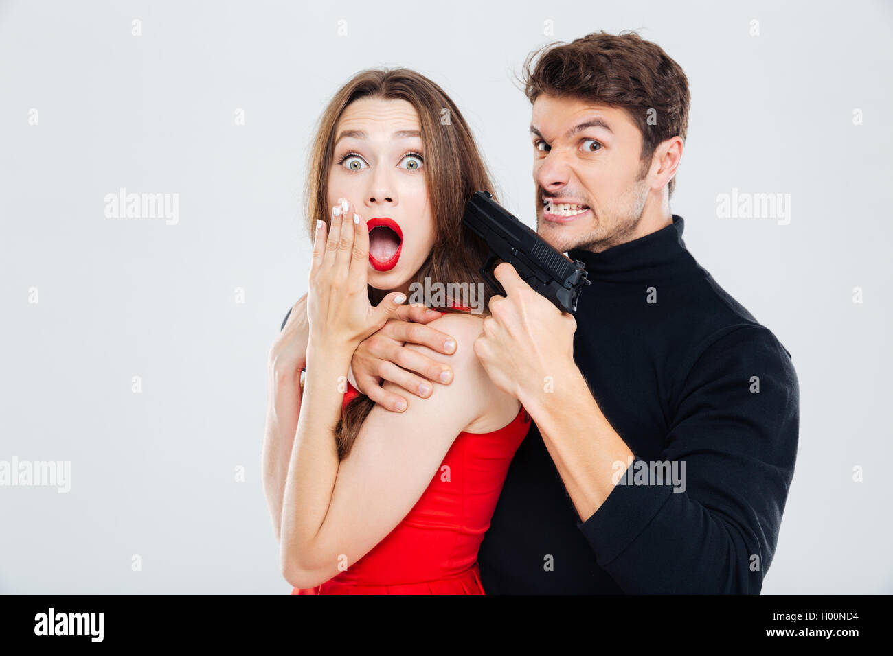Mad criminal young man threatening to scared young woman with gun Stock ...