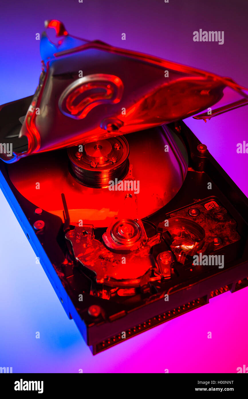 A broken computer hard drive with casing cracked open and disc visible ...