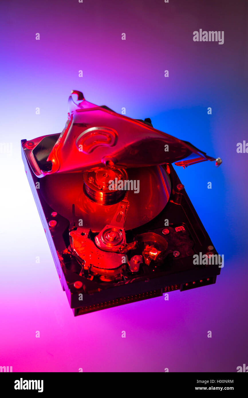 A broken computer hard drive with casing cracked open and disc visible ...
