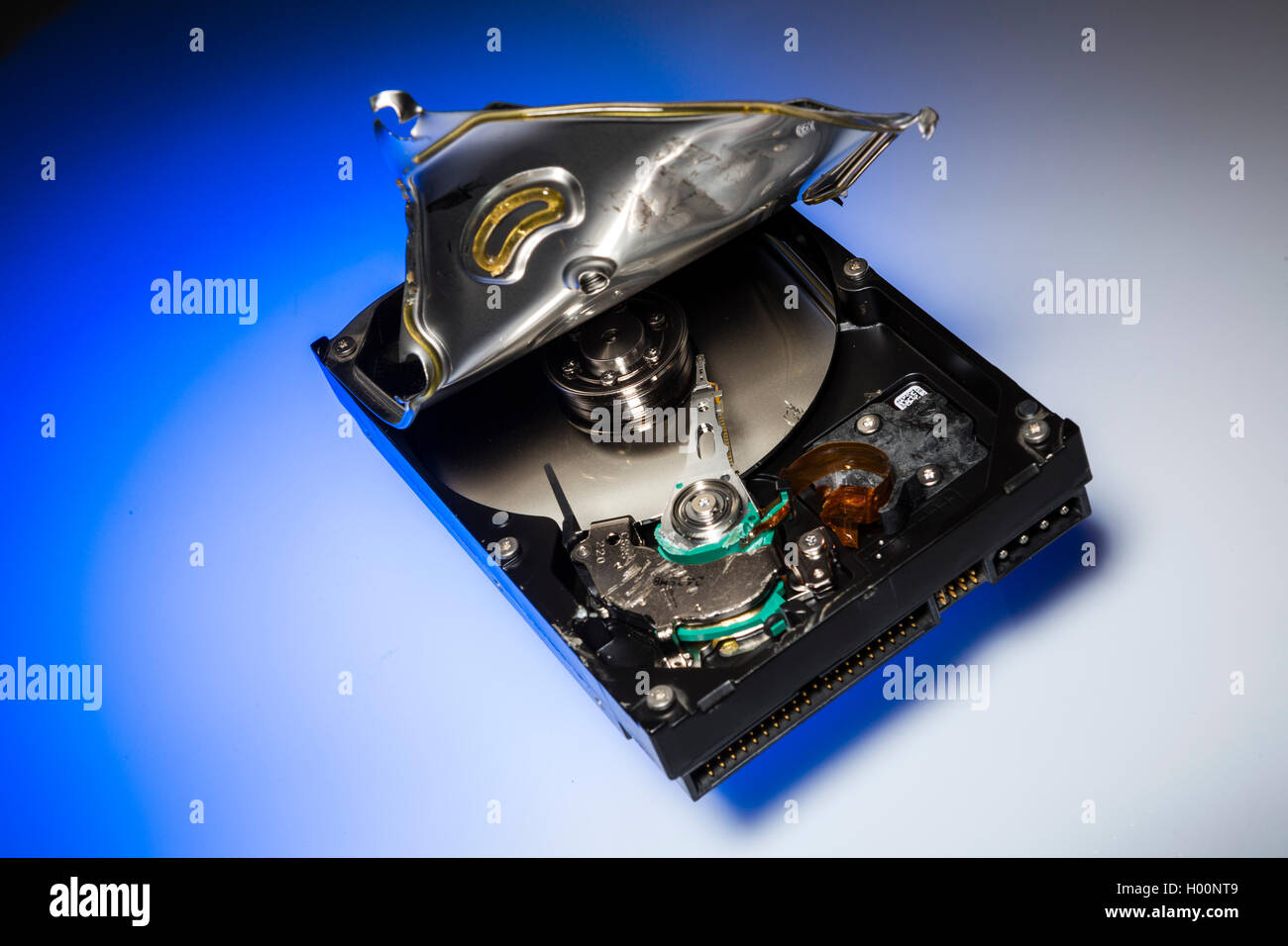 A broken computer hard drive with casing cracked open and disc visible ...