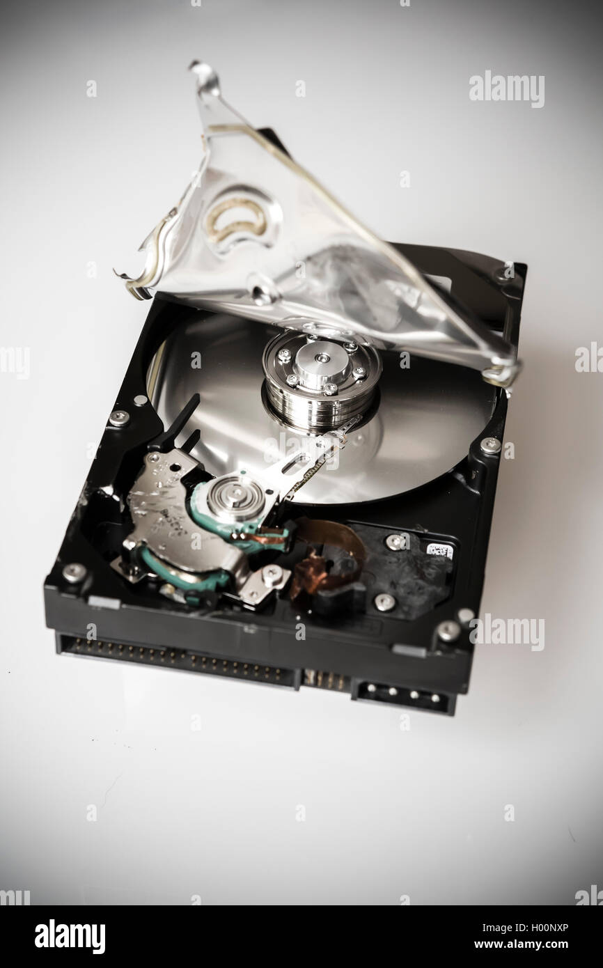 A broken computer hard drive with casing cracked open and disc visible ...