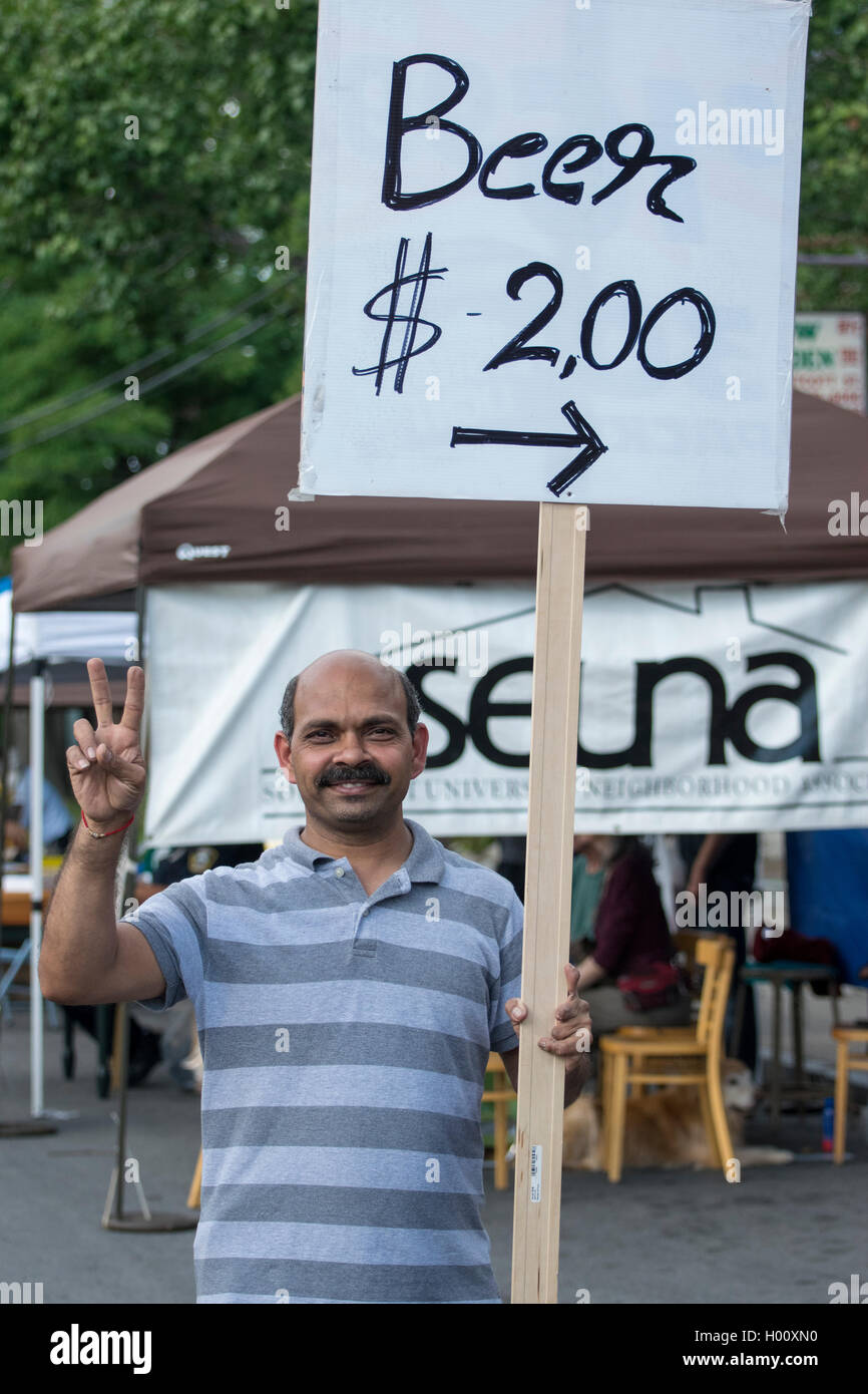 A man holding a Two Dollar Beer sign at a street fair Stock Photo - Alamy