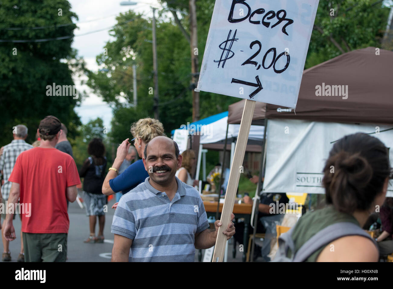 A man holding a Two Dollar Beer sign at a street fair Stock Photo - Alamy