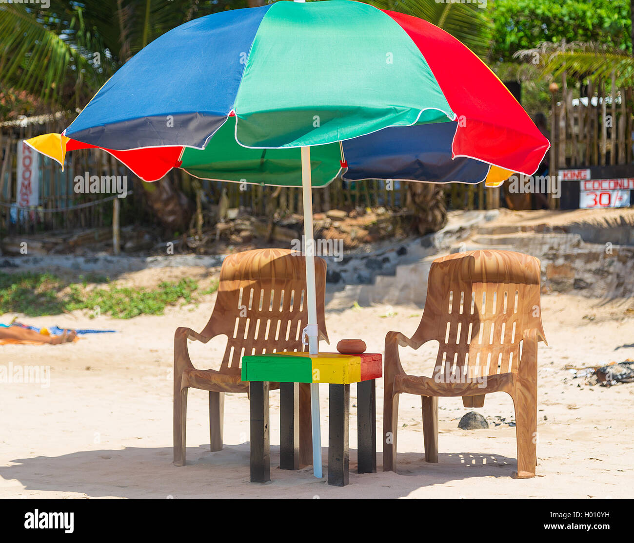 Table, chairs and colourful parasol on sandy beach in the tropics Stock ...