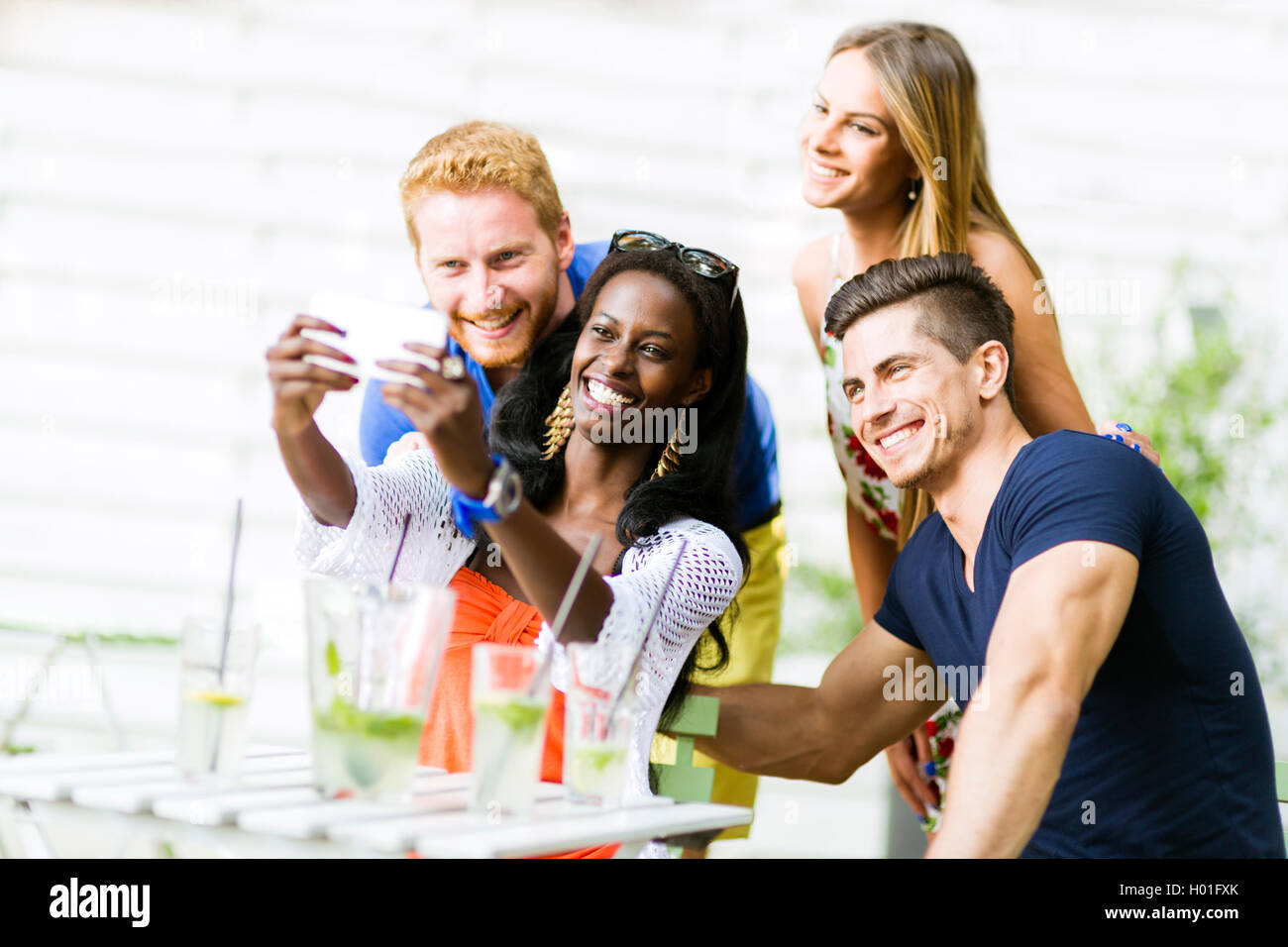 A group of friends sitting a table and talking smiling while taking ...