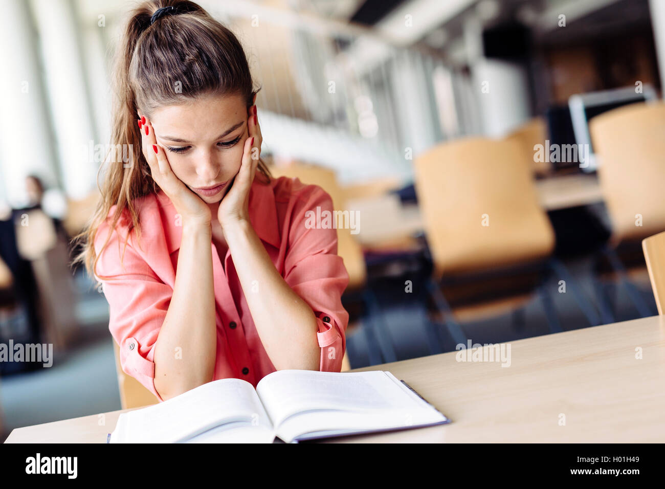Female student studying and reading in a library but is having a hard ...