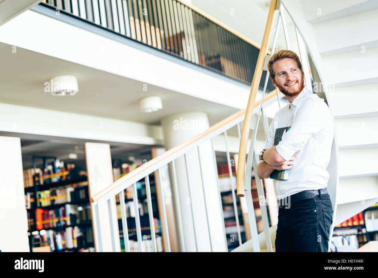 Handsome smart guy reading a book in a library Stock Photo - Alamy
