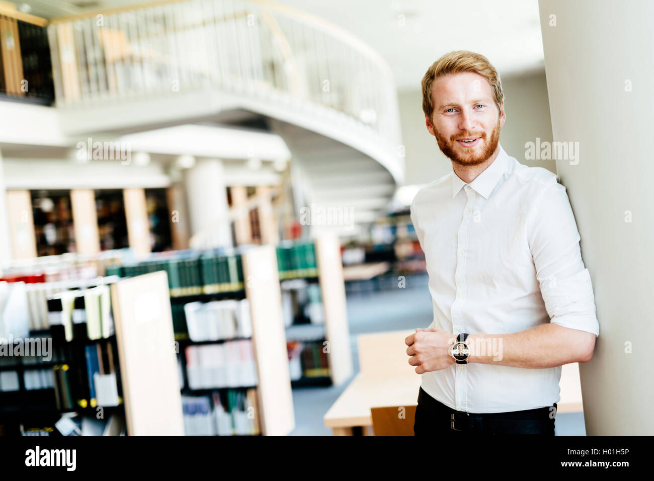 Handsome intelligent male student smiling in library Stock Photo - Alamy