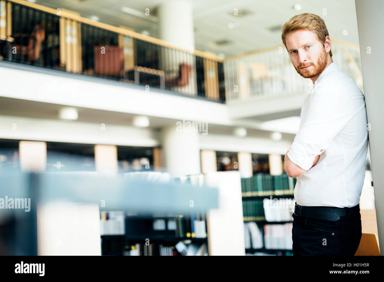 Portrait of a serious handsome student in library Stock Photo - Alamy
