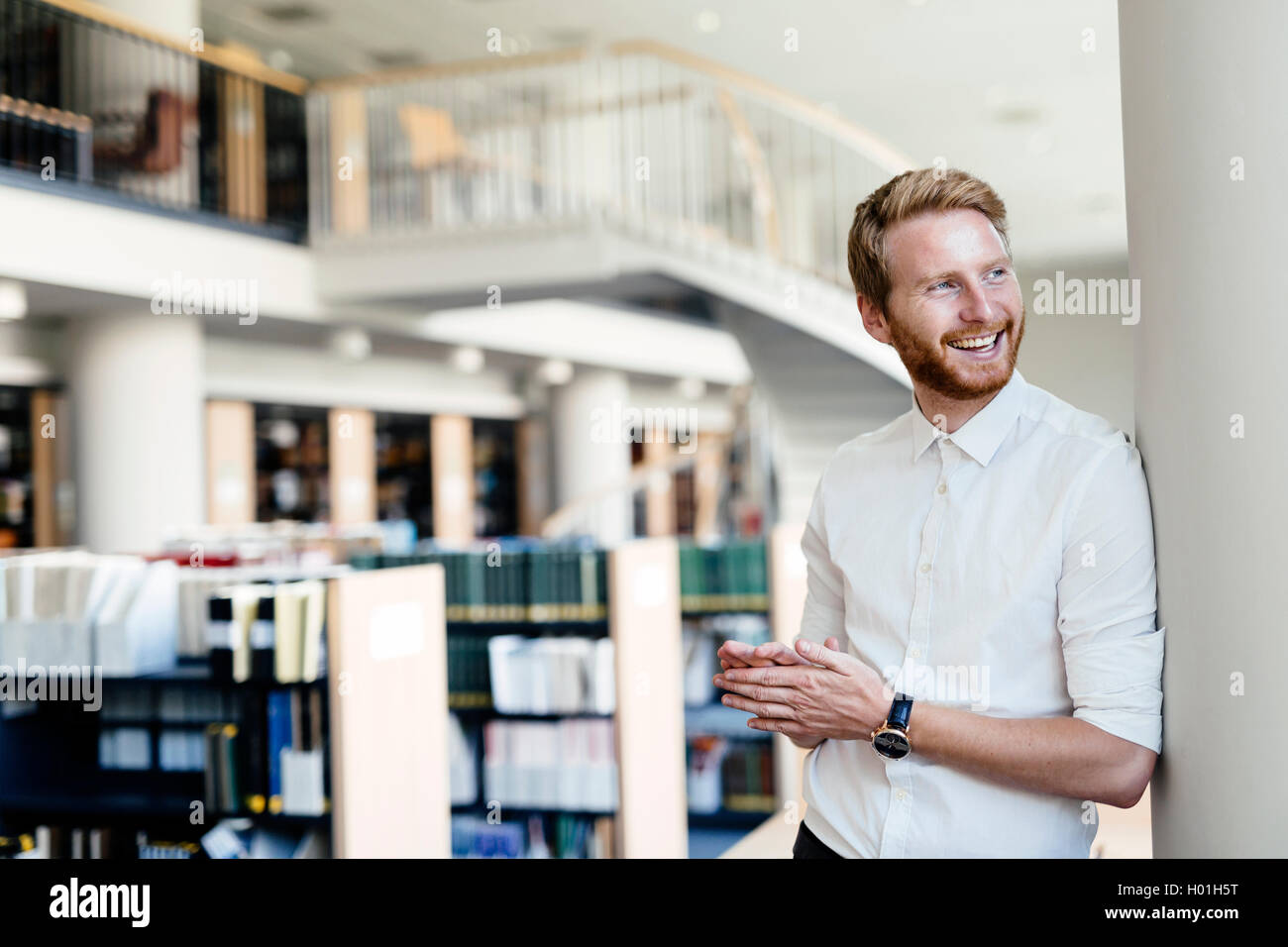 Handsome intelligent male student smiling in library Stock Photo - Alamy
