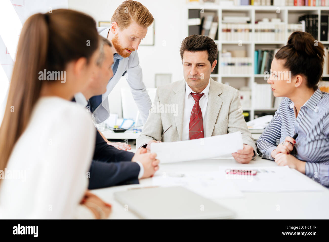 Coworkers working on project together in office Stock Photo - Alamy