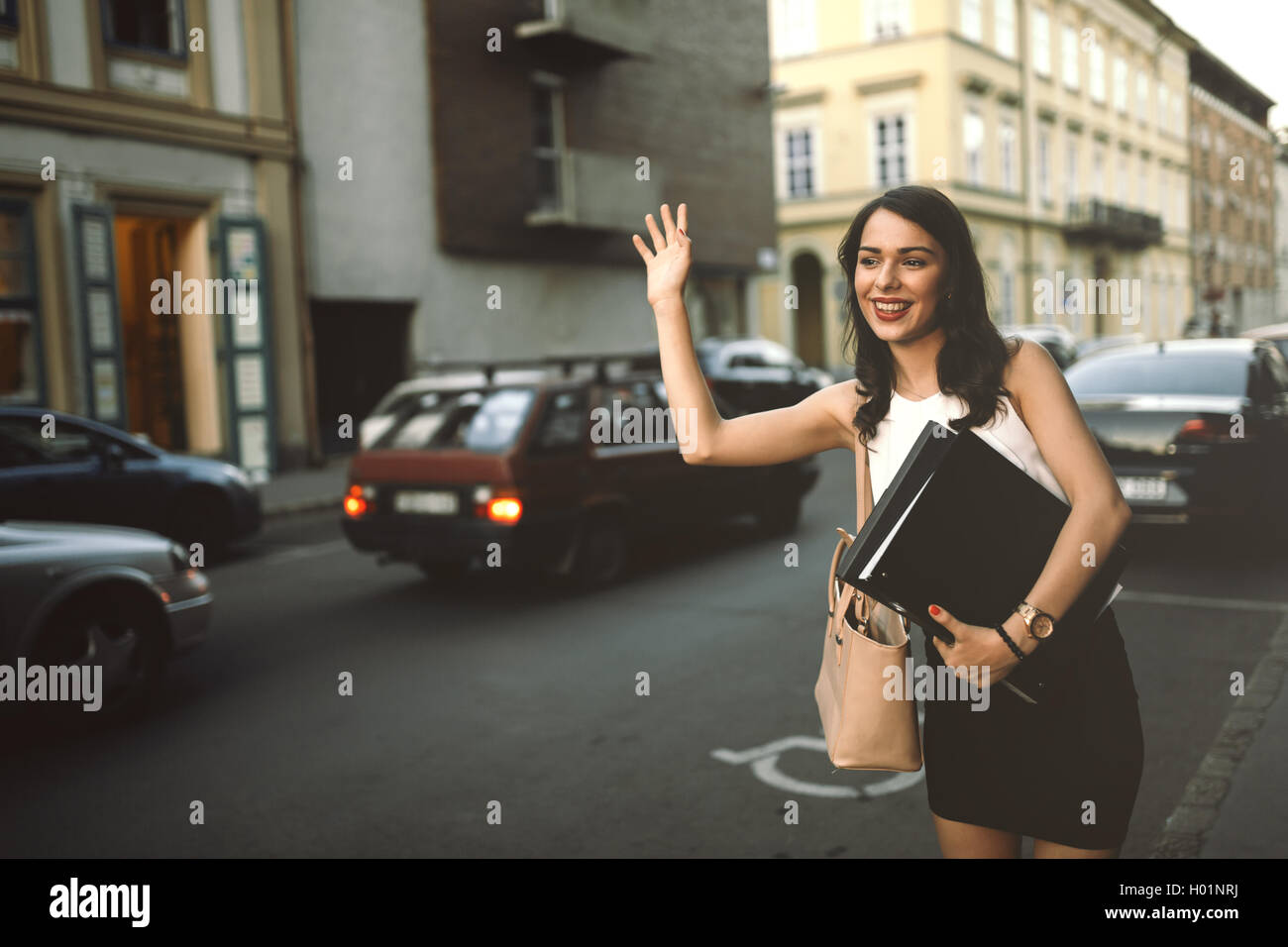 Businesswoman catching a taxi by waving Stock Photo - Alamy