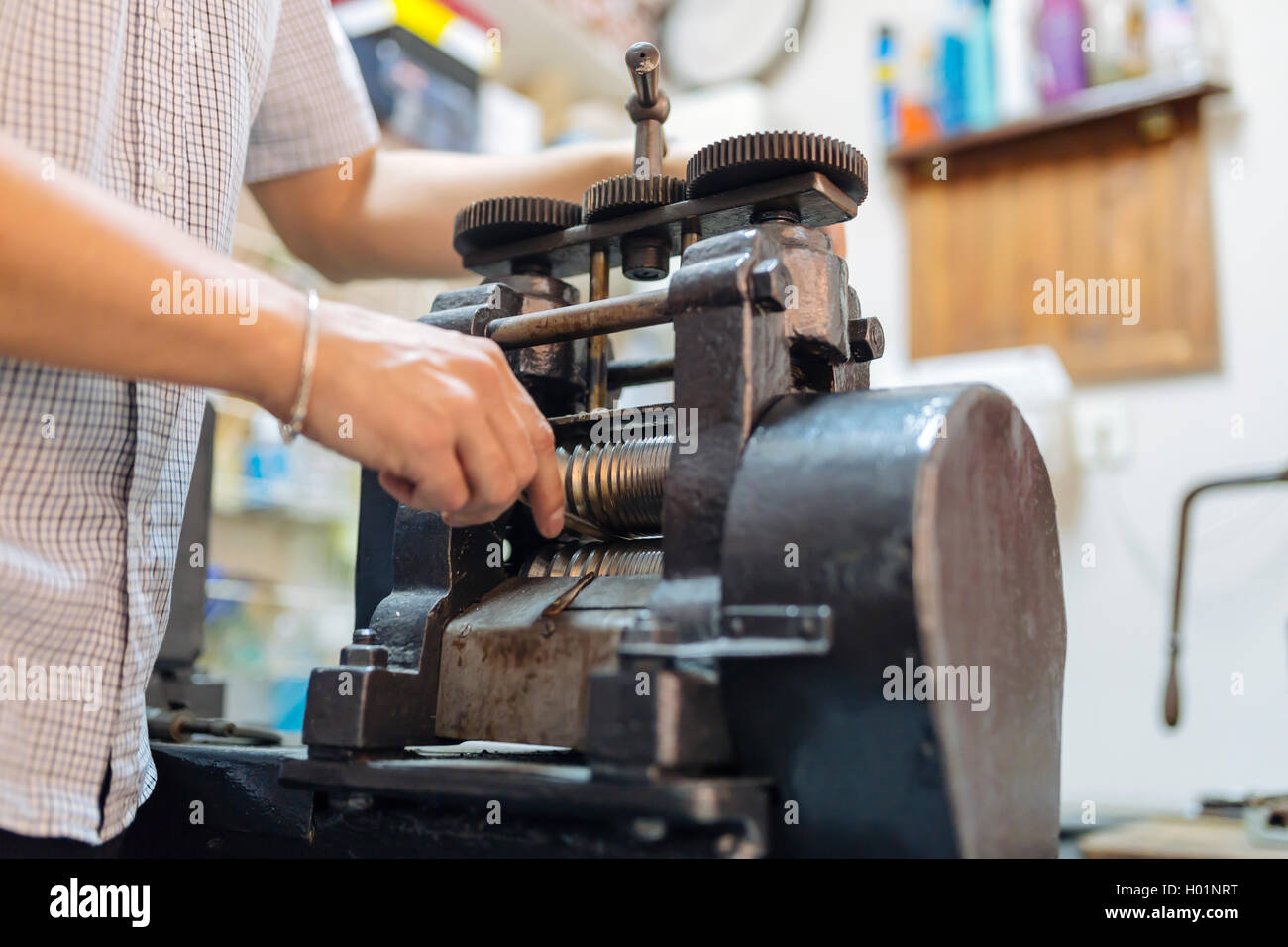Goldsmith using machine to make metal thinner Stock Photo - Alamy