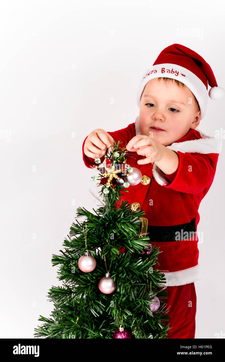 Baby boy dressed as Santa Claus putting the star on the top of ...