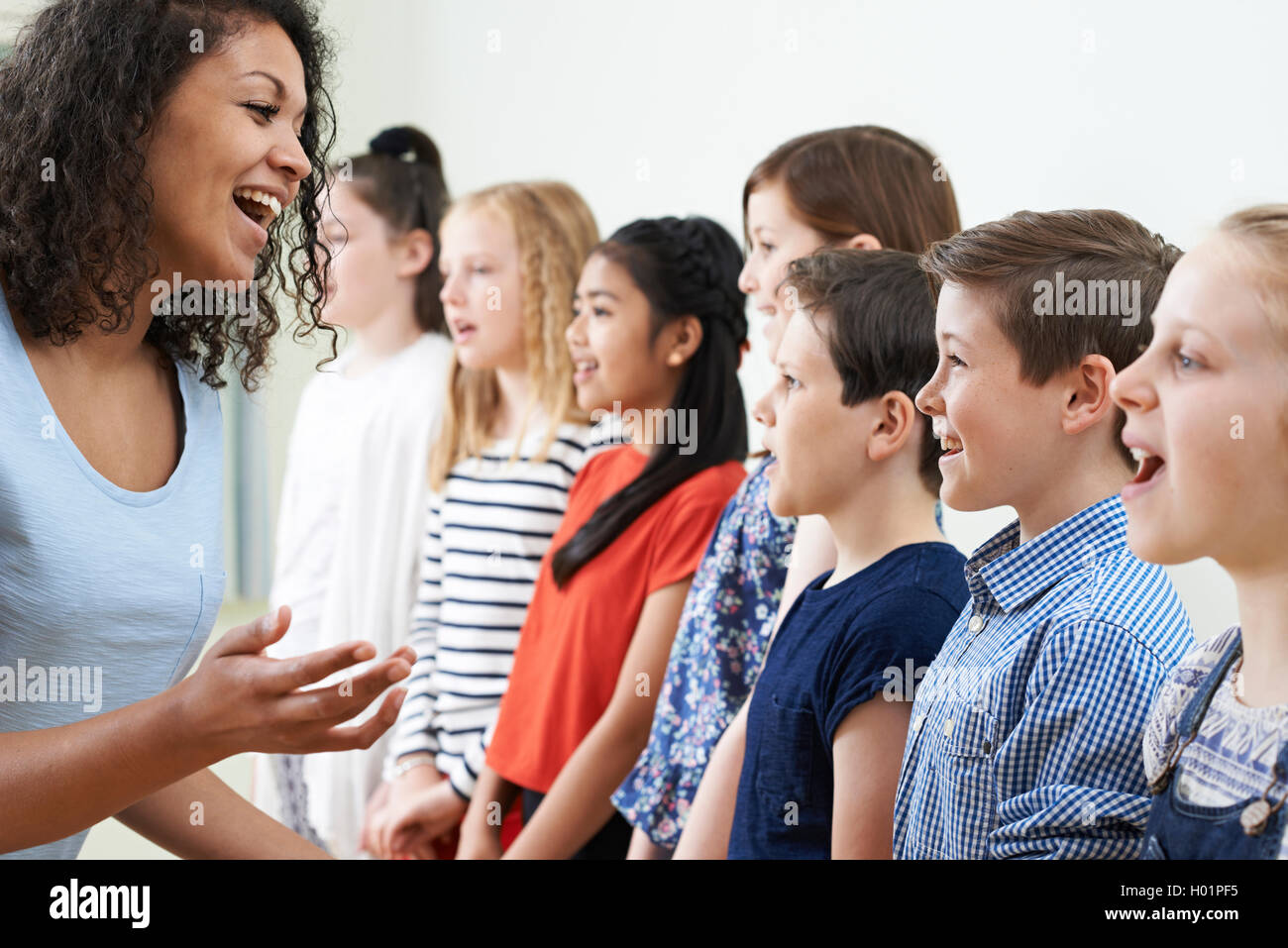 Children In School Choir Being Encouraged By Teacher Stock Photo - Alamy