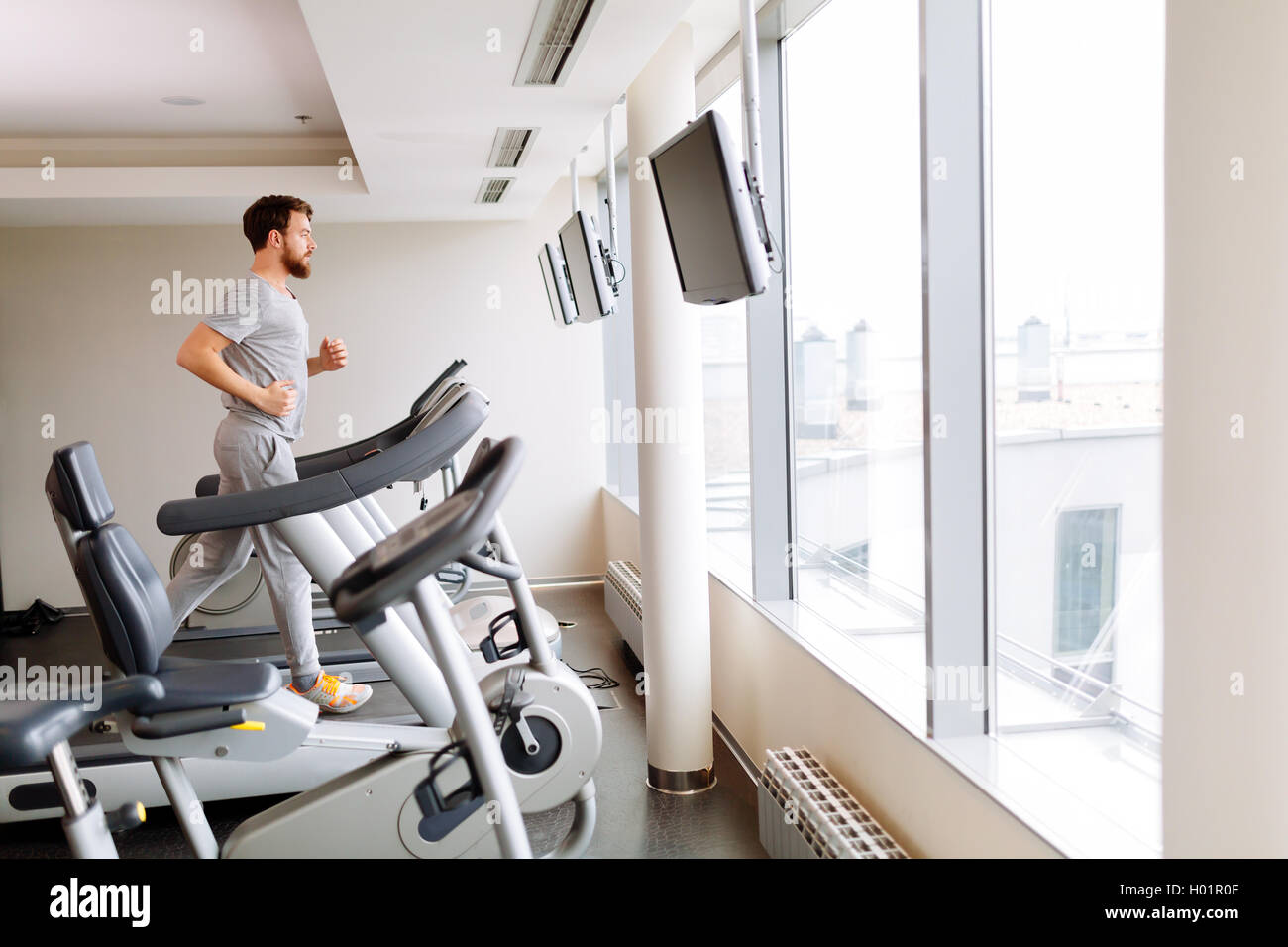 Handsome man running on treadmill in gym Stock Photo - Alamy