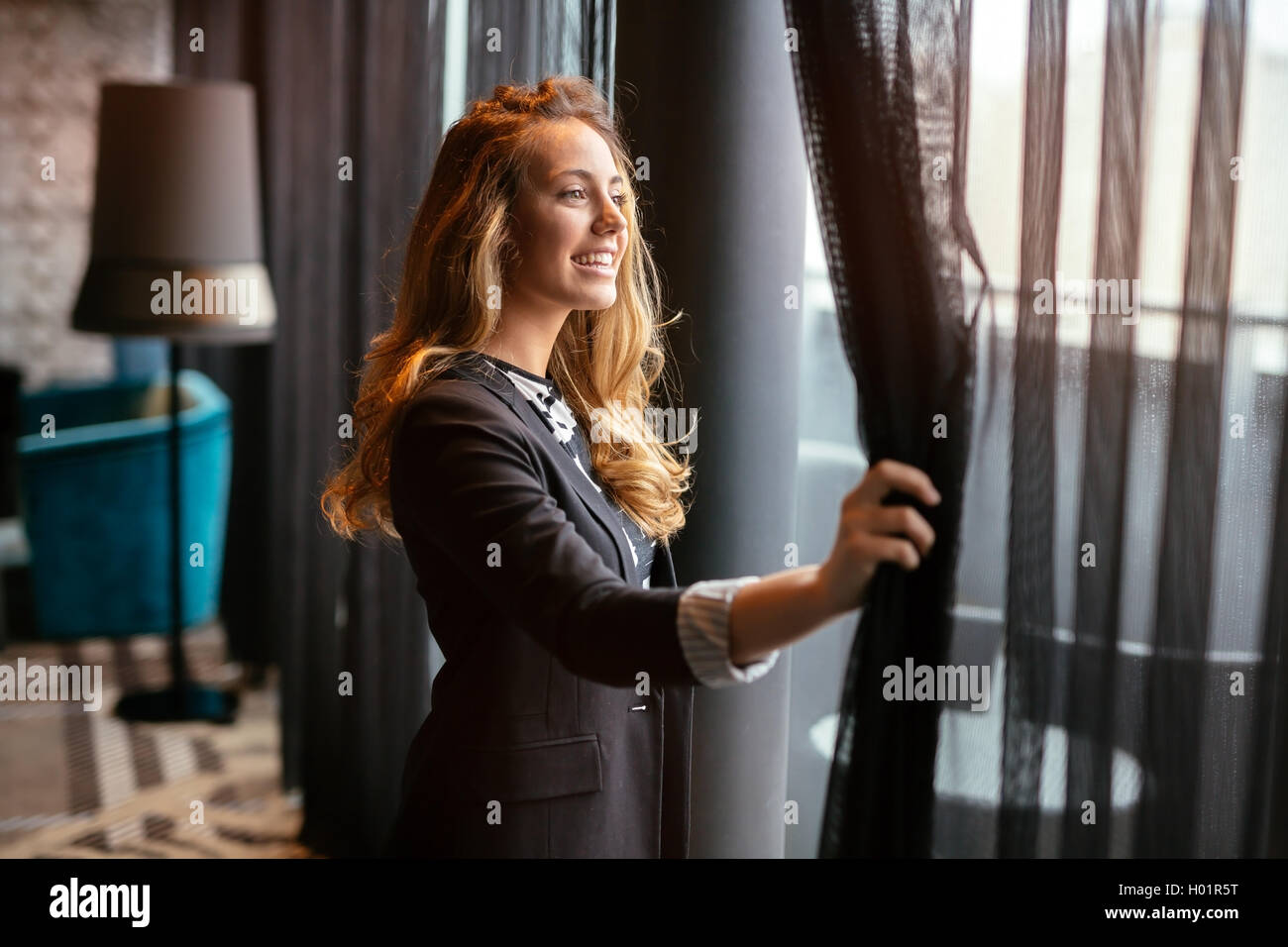 Glamorous happy woman staring through window Stock Photo - Alamy