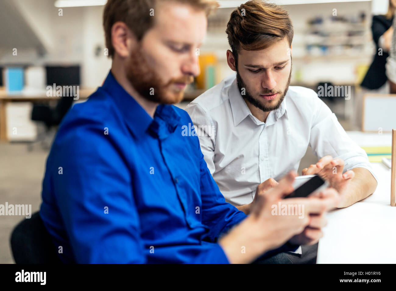 Handsome businessmen using phones and calling partners while sitting at ...