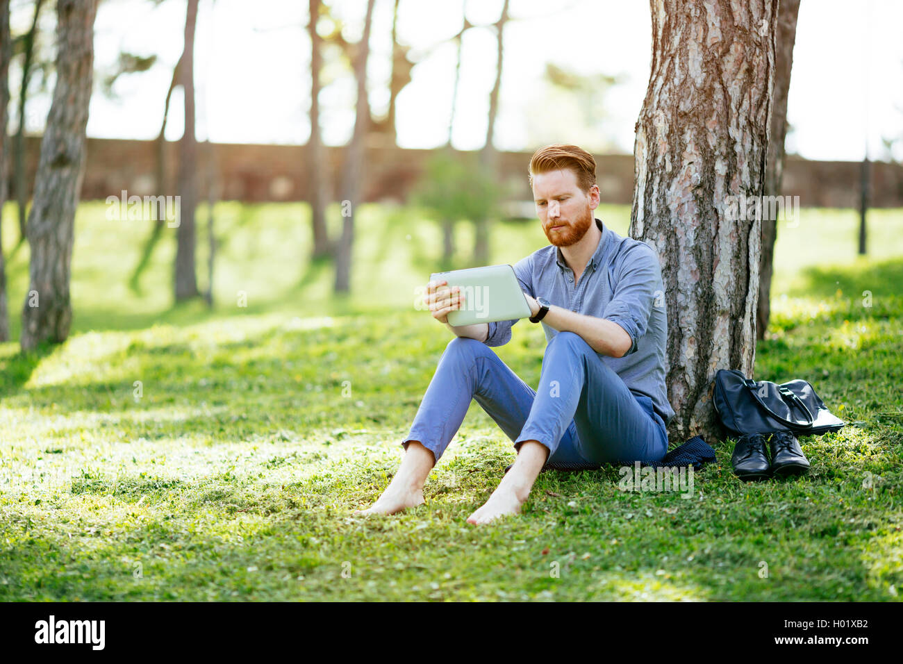 Handsome student reading and studying in park Stock Photo - Alamy